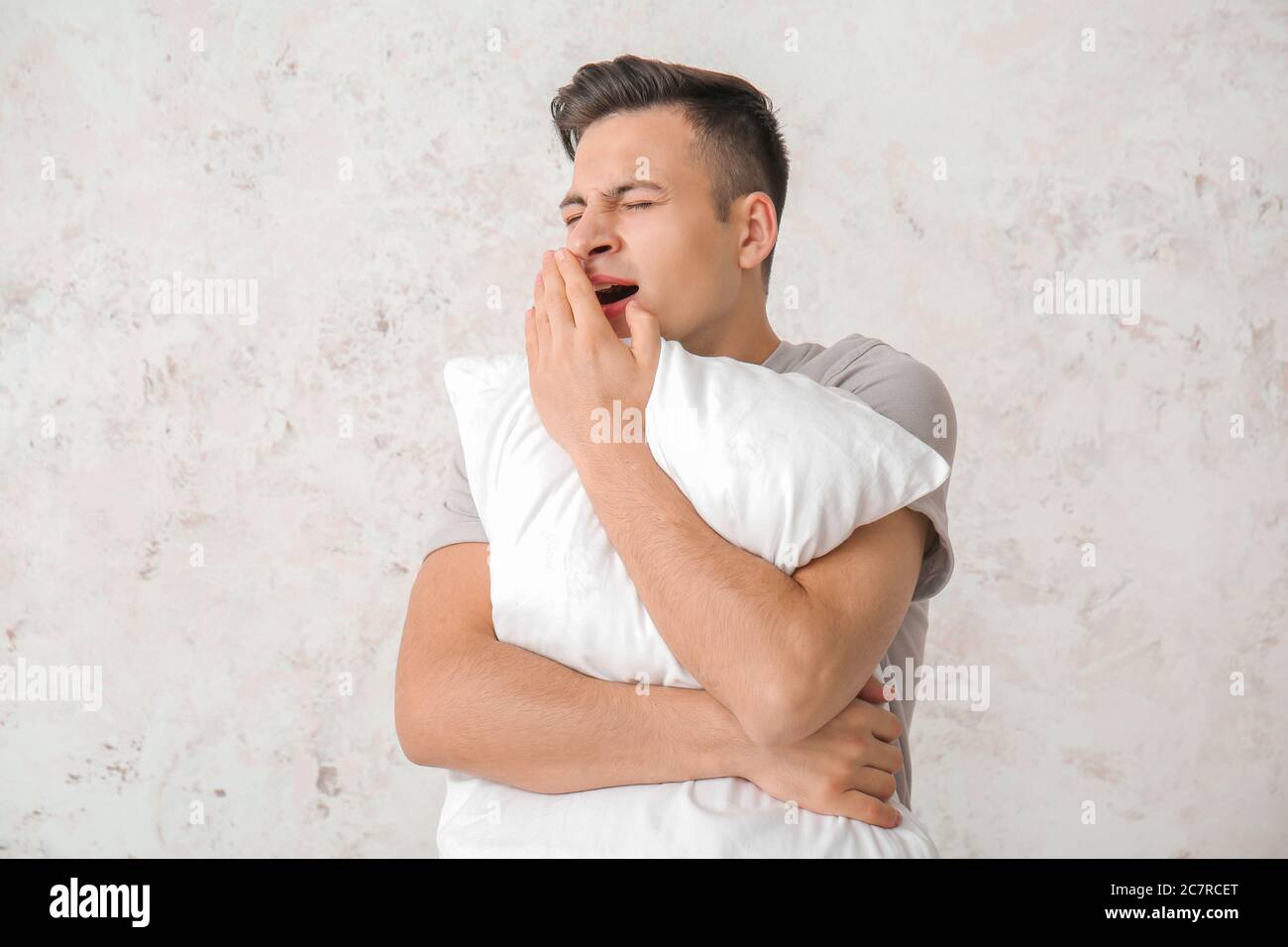Tired man with pillow on light background. Concept of sleep deprivation ...