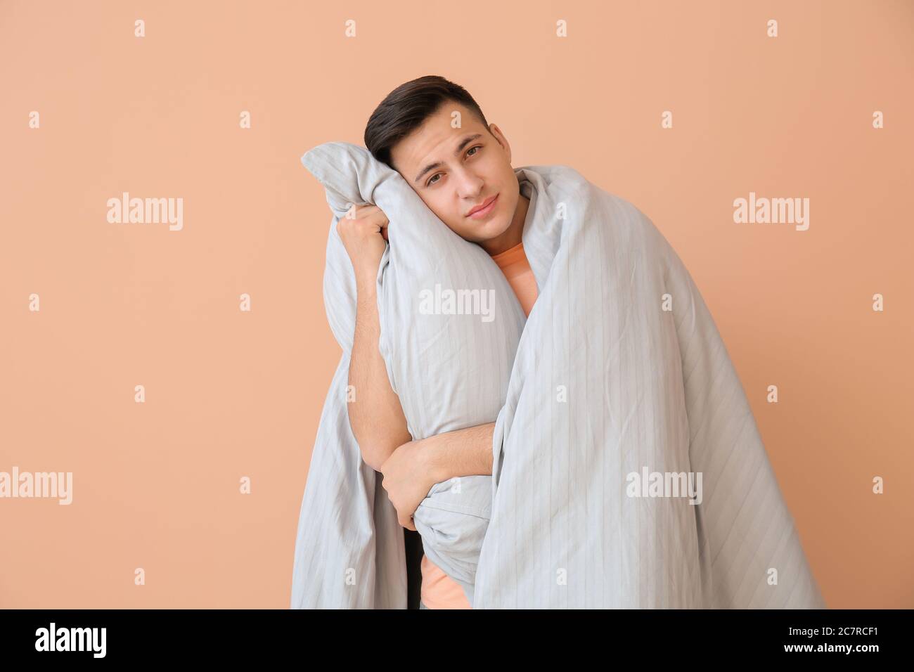 Tired man with bedding on color background. Concept of sleep ...
