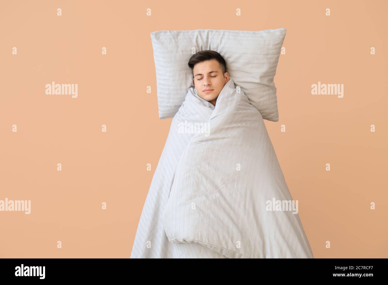 Tired man with bedding on color background. Concept of sleep ...
