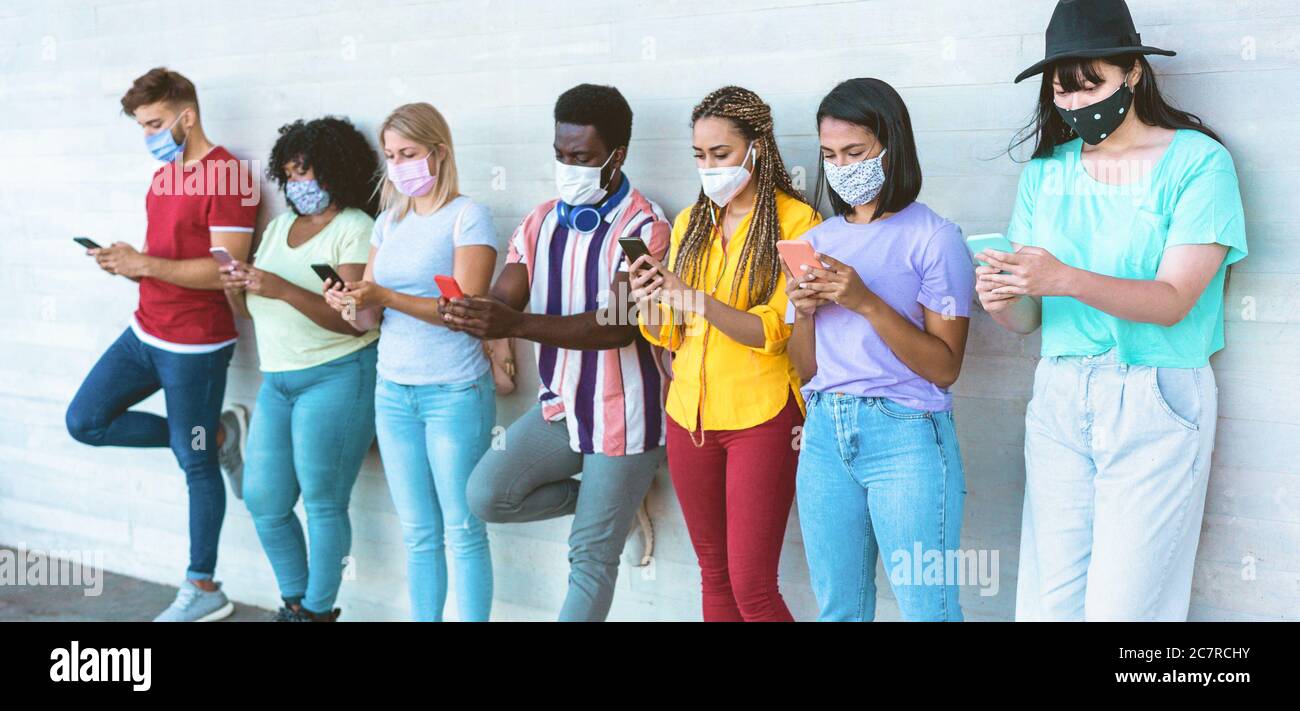 Young people wearing face safety masks using smart mobile phones while ...
