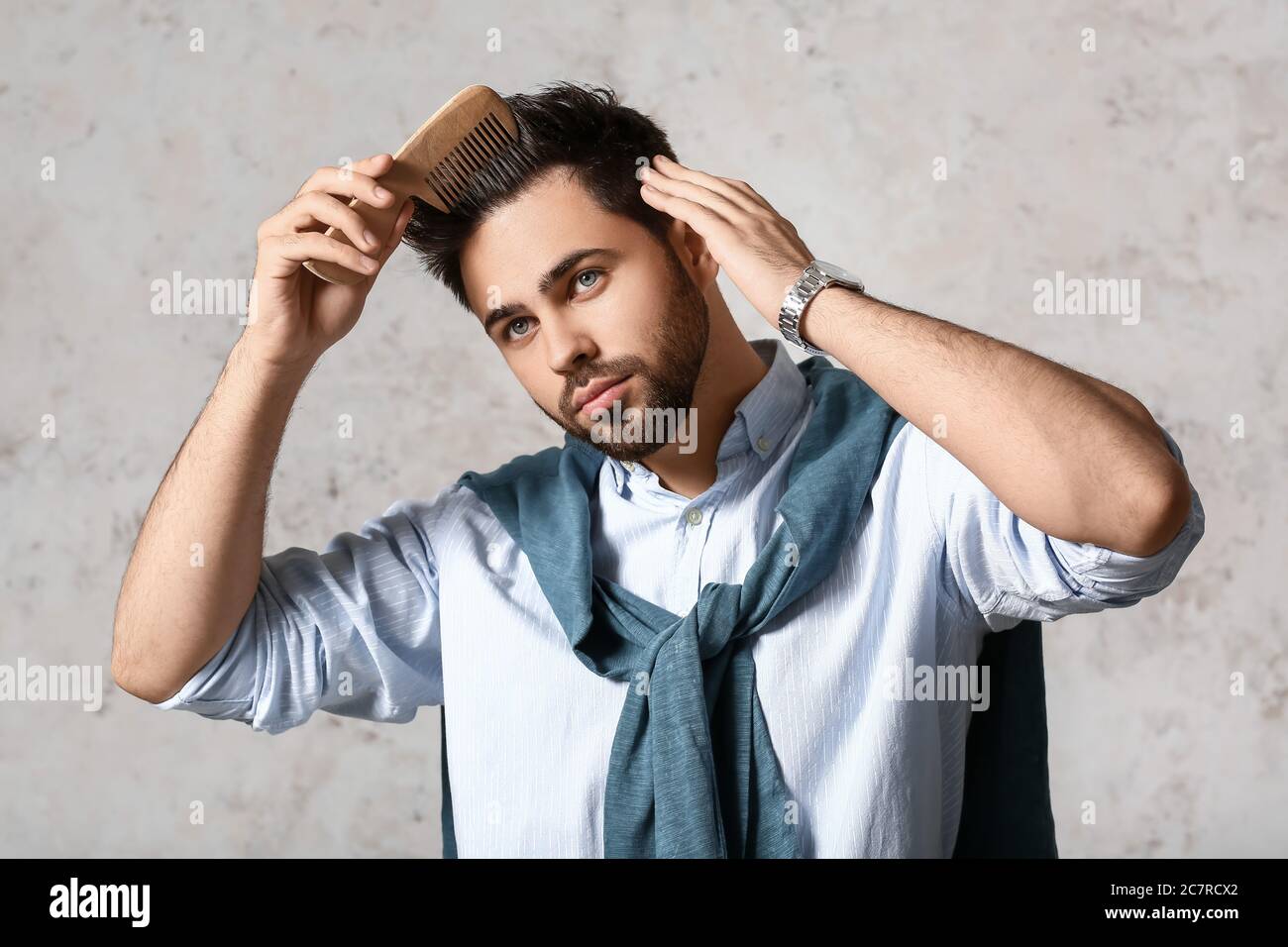 Handsome man combing hair on light background Stock Photo - Alamy