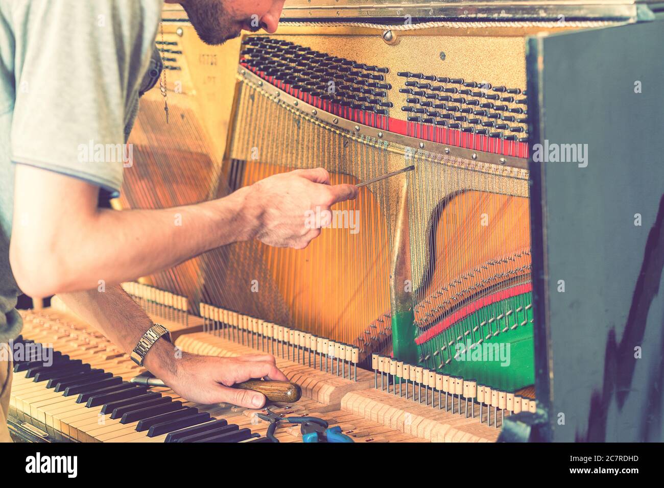 Piano tuning process. closeup of hand and tools of tuner working on ...