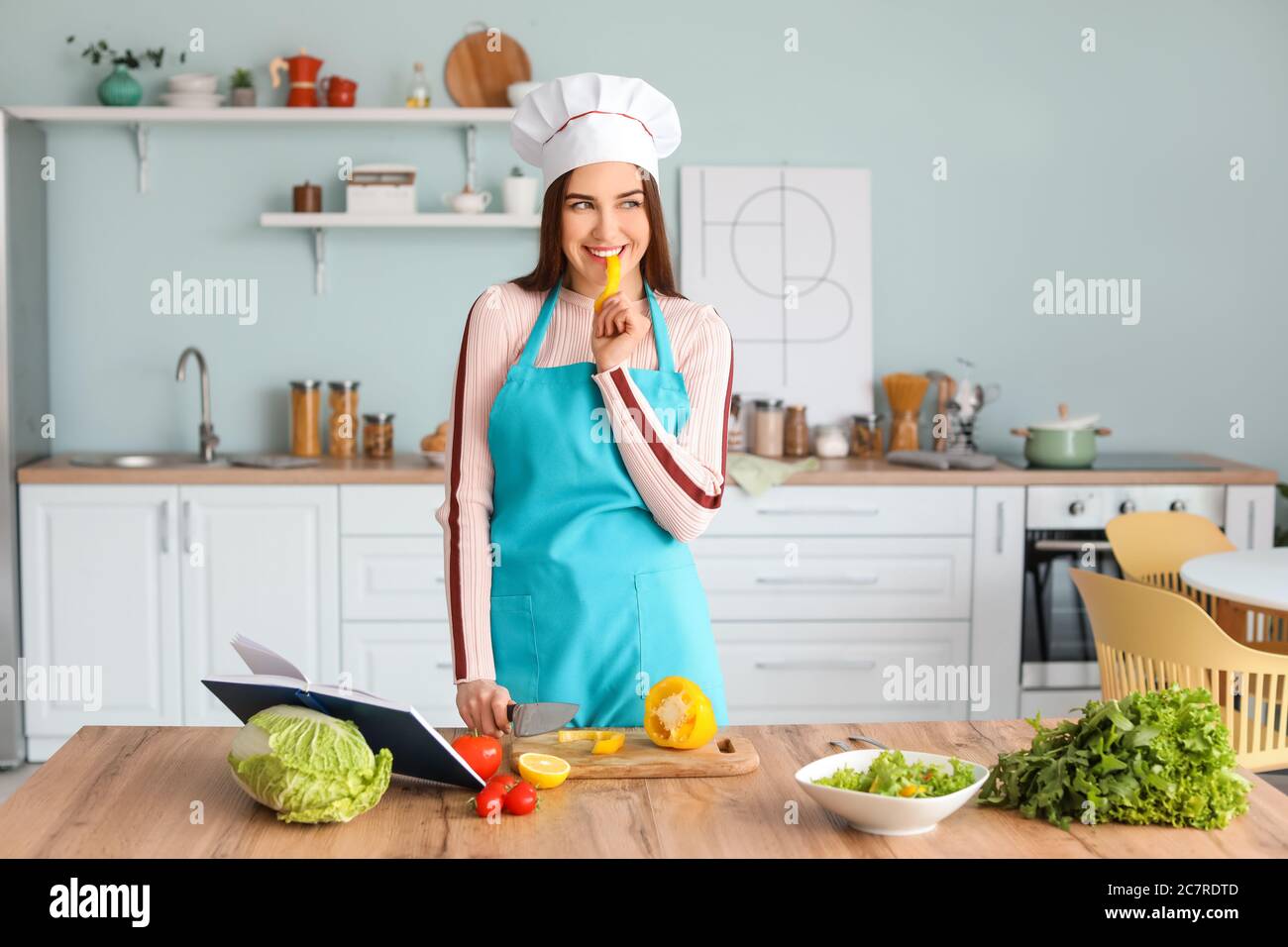 Young woman with recipe book cooking in kitchen Stock Photo - Alamy