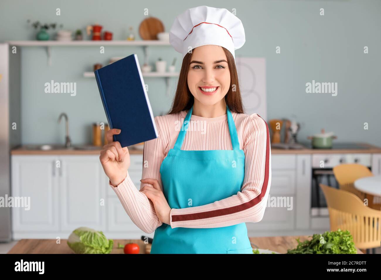 Young woman with recipe book in kitchen Stock Photo - Alamy