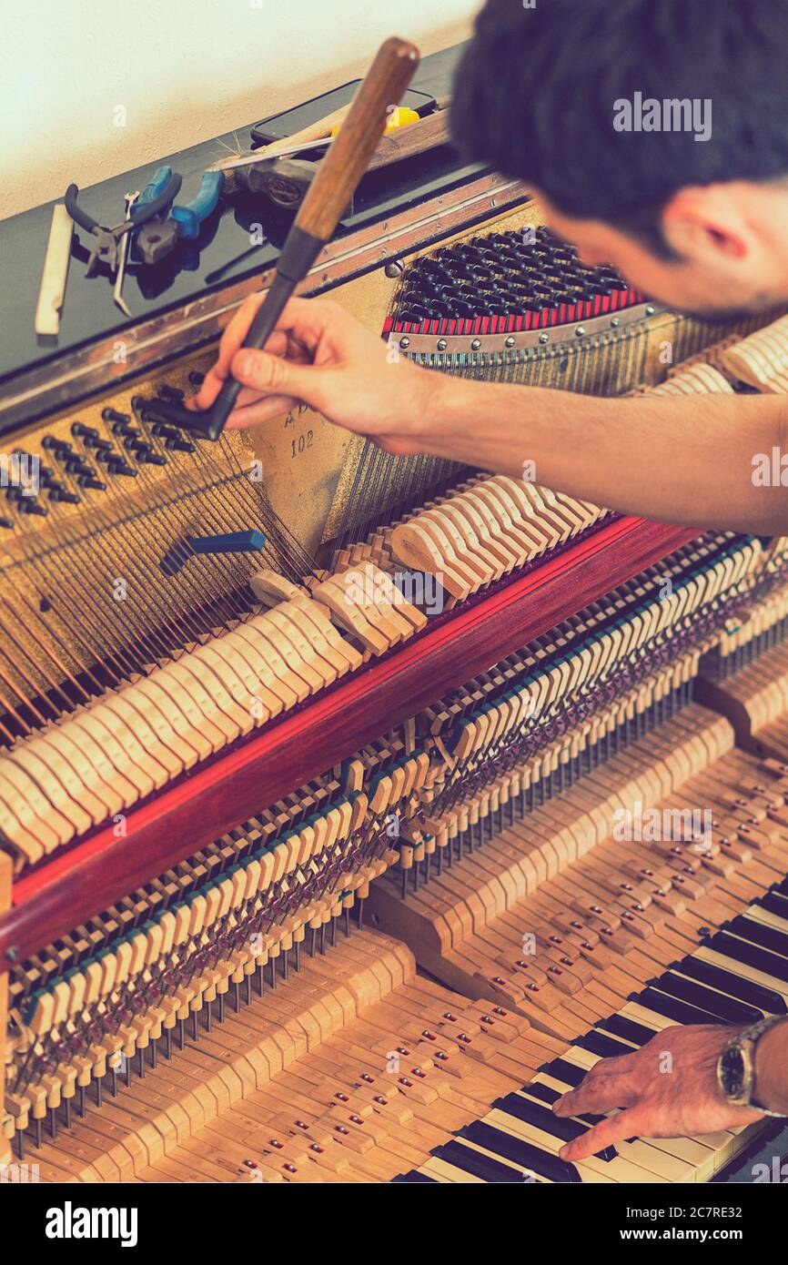 Piano tuning process. closeup of hand and tools of tuner working on ...