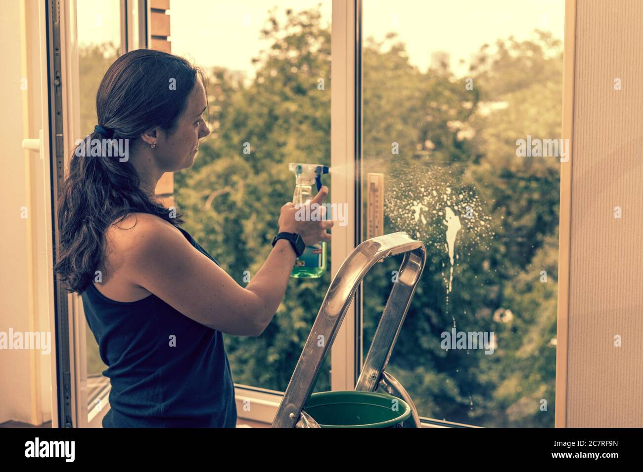 Back view of the young woman who washing the window with rag and window ...