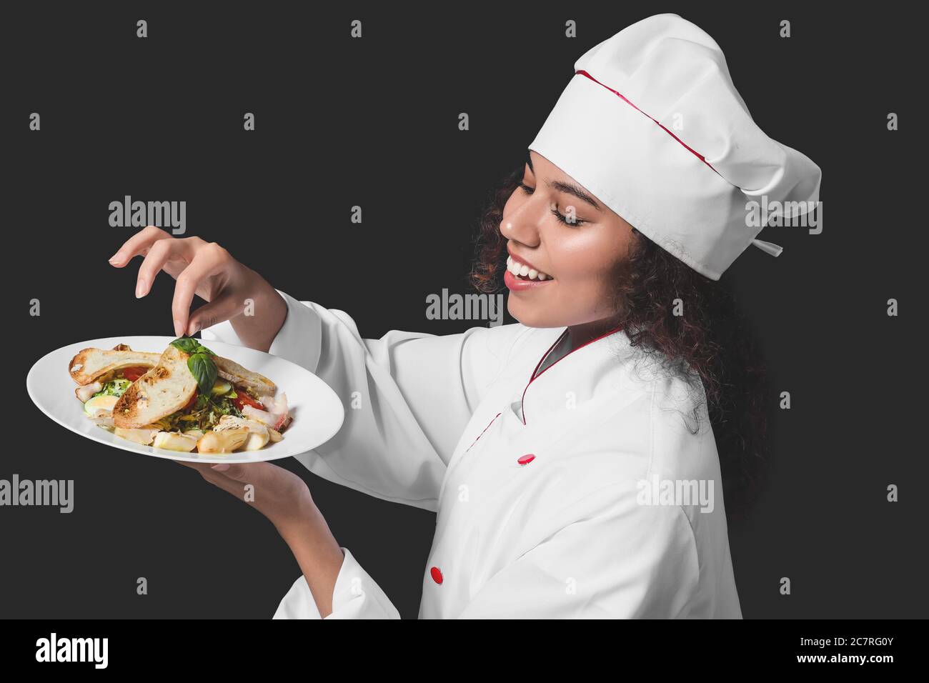 Female African-American chef with tasty dish on dark background Stock ...