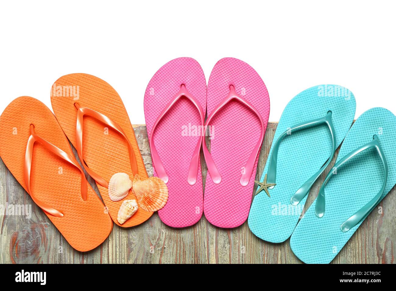 Flip-flops and shells on wooden surface against white background Stock ...