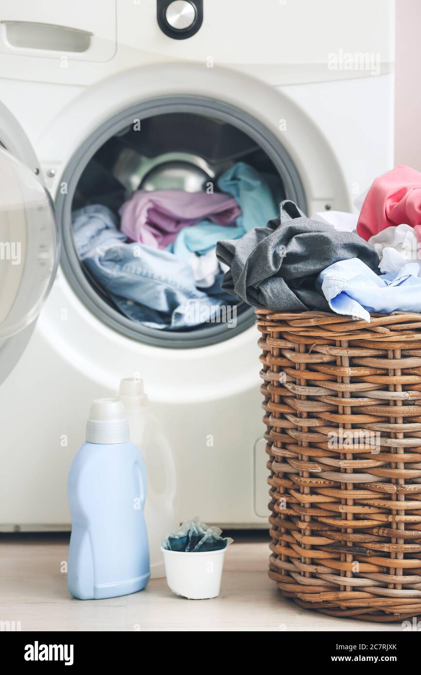 Washing machine and basket with dirty clothes in home laundry room ...