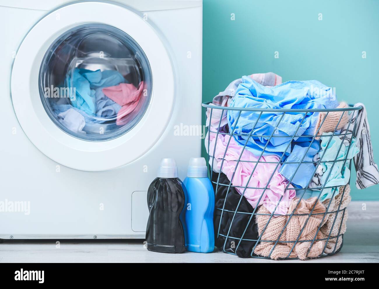 Washing machine and basket with dirty clothes in home laundry room ...