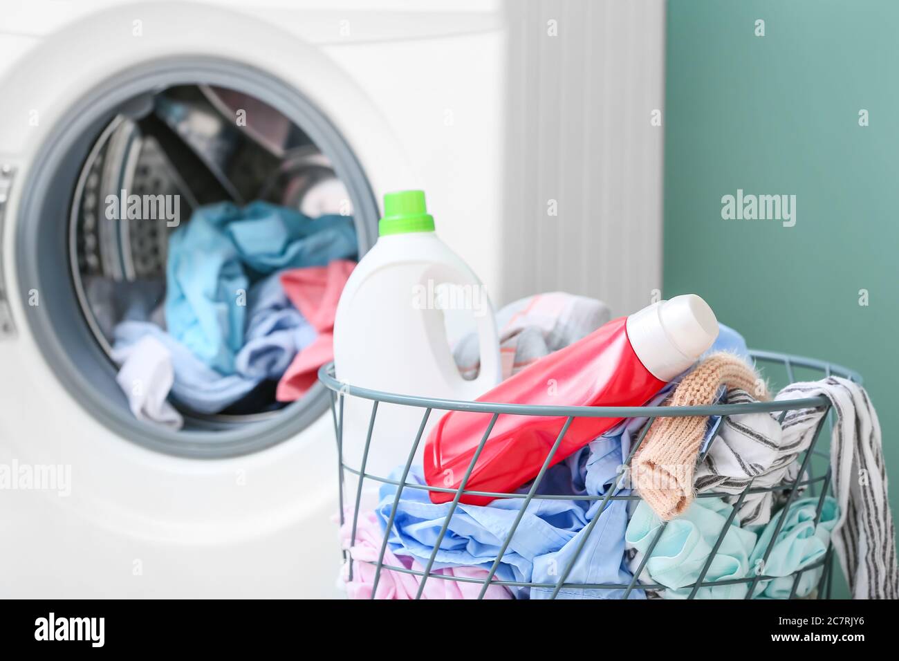 Washing machine with dirty clothes and detergents in home laundry room ...