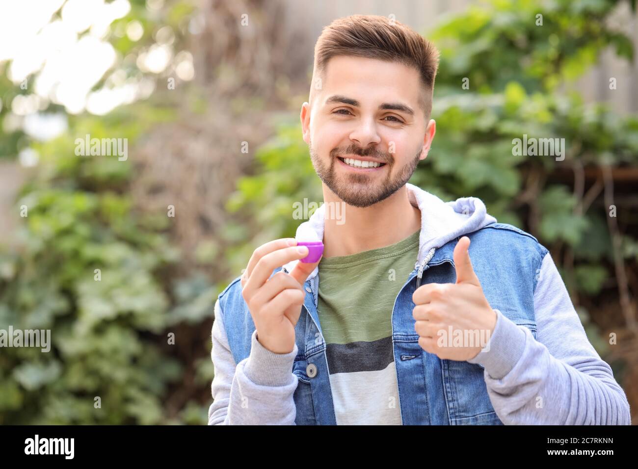 Handsome young man with lip balm showing thumb-up outdoors Stock Photo ...