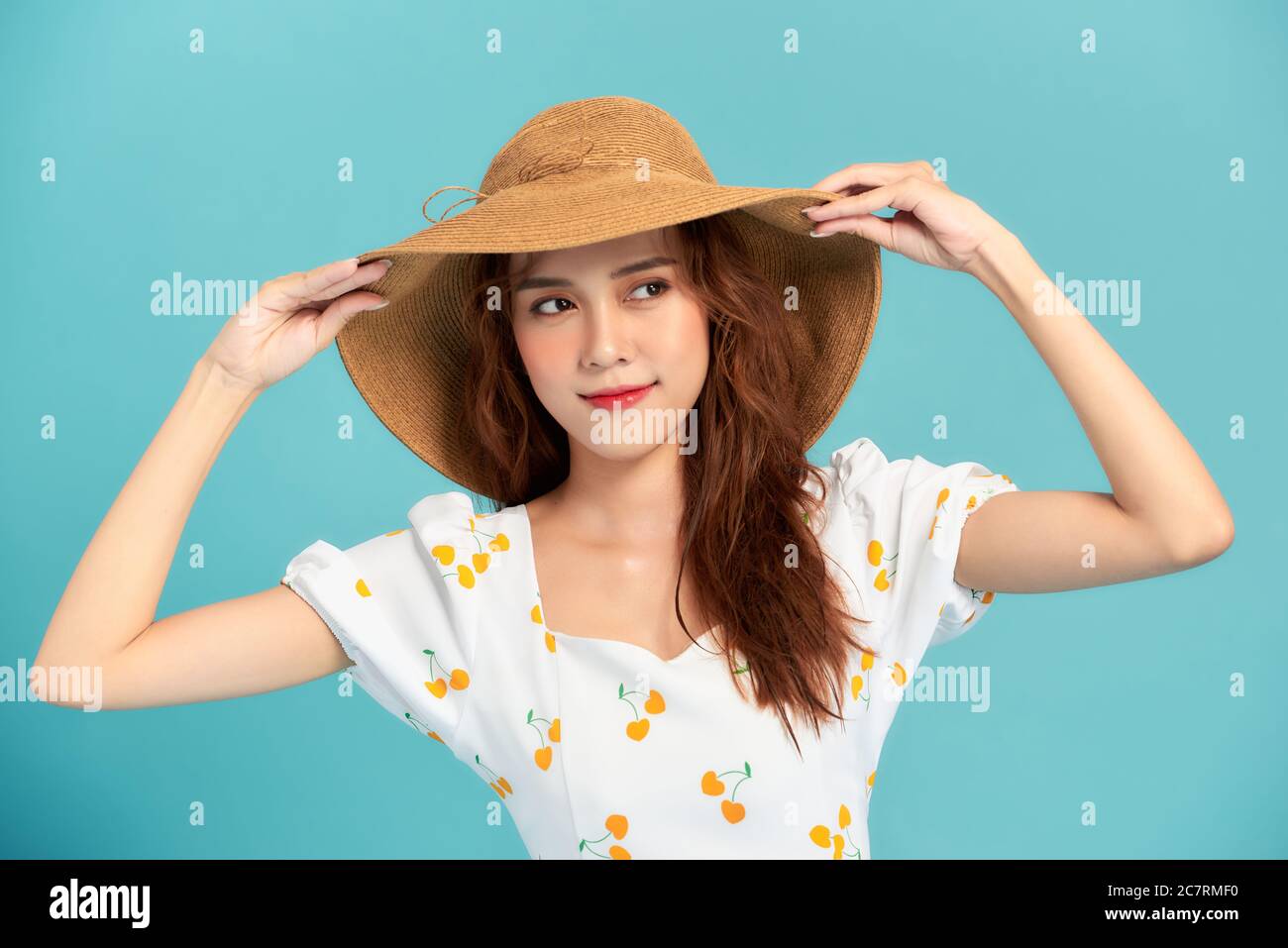 Young beautiful girl wearing a straw hat stands and smiles isolated ...