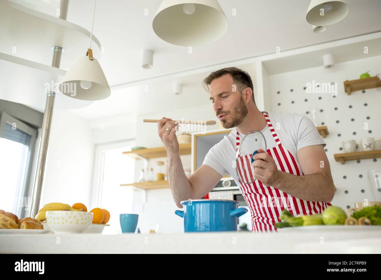 Man wearing a white apron with red lines and cooking something in the ...