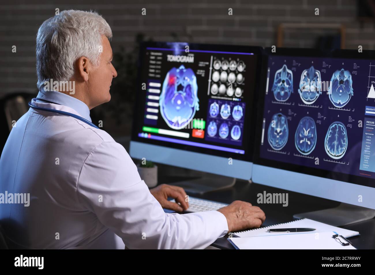 Senior neurologist with MRI scan of human head on screen of computer ...