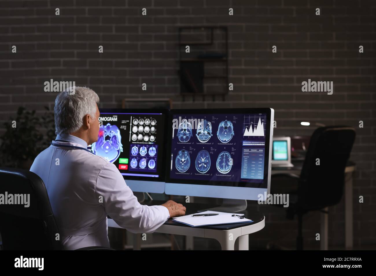 Senior neurologist with MRI scan of human head on screen of computer ...
