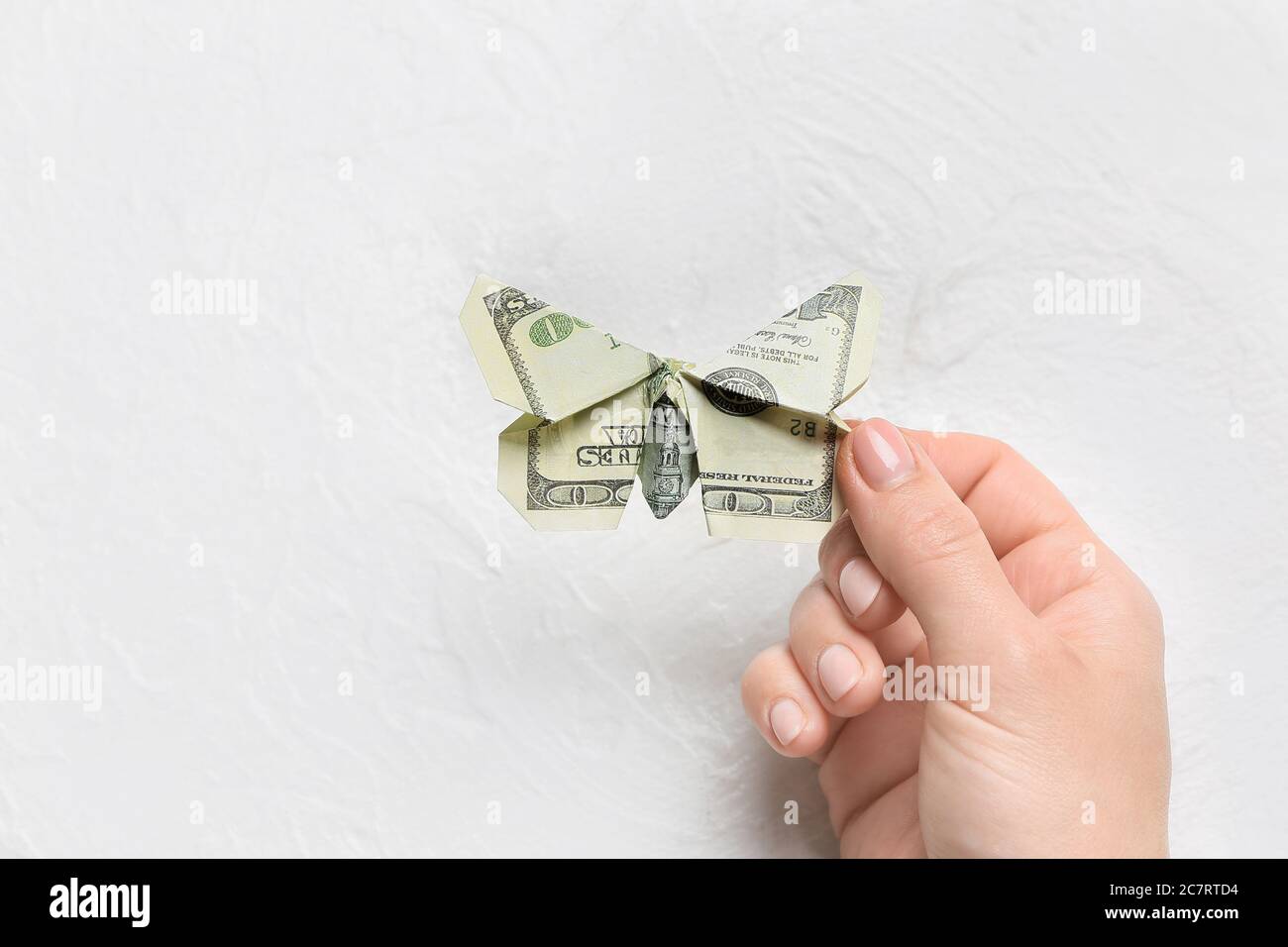 Female hand with origami butterfly made of dollar banknote on white ...