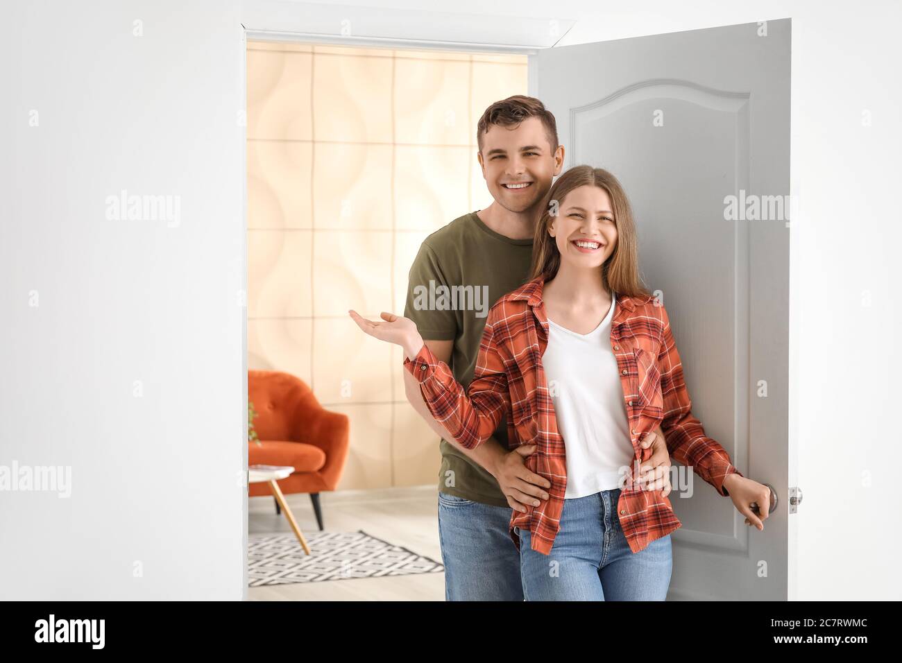 Happy couple inviting guest at their new home Stock Photo - Alamy