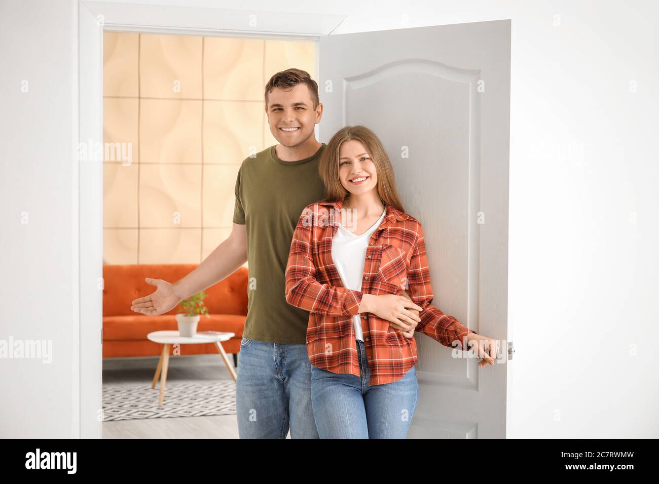 Happy couple inviting guest at their new home Stock Photo - Alamy