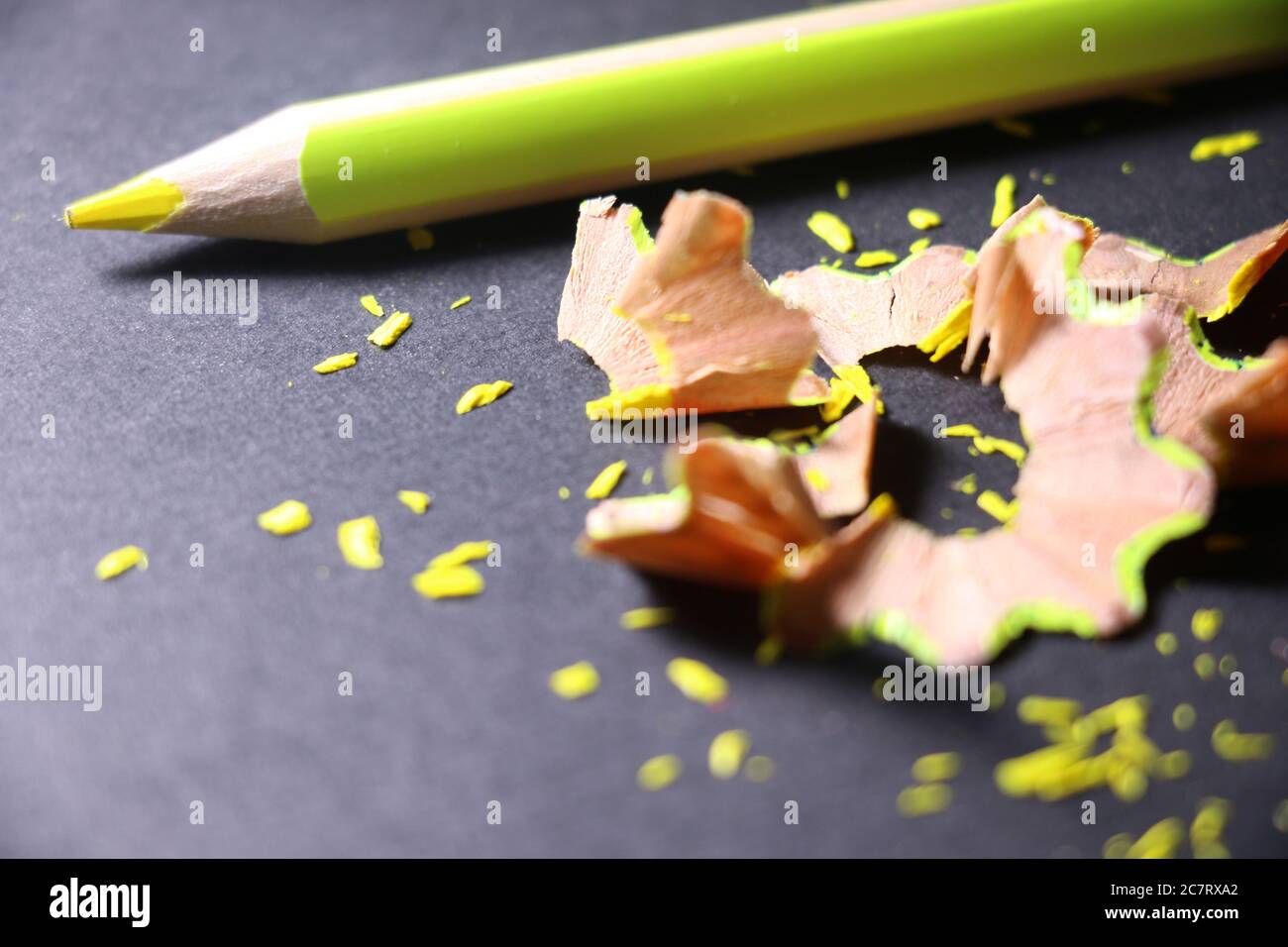 Closeup shot of a neon yellow pencil with the shavings next to it on a ...