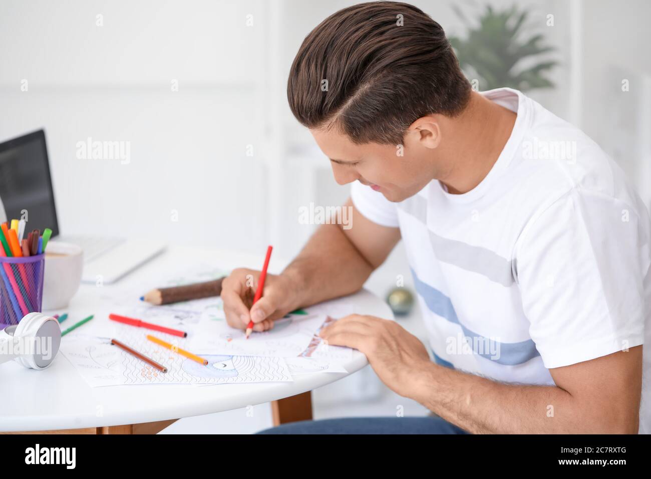 Young man coloring pictures at home Stock Photo - Alamy