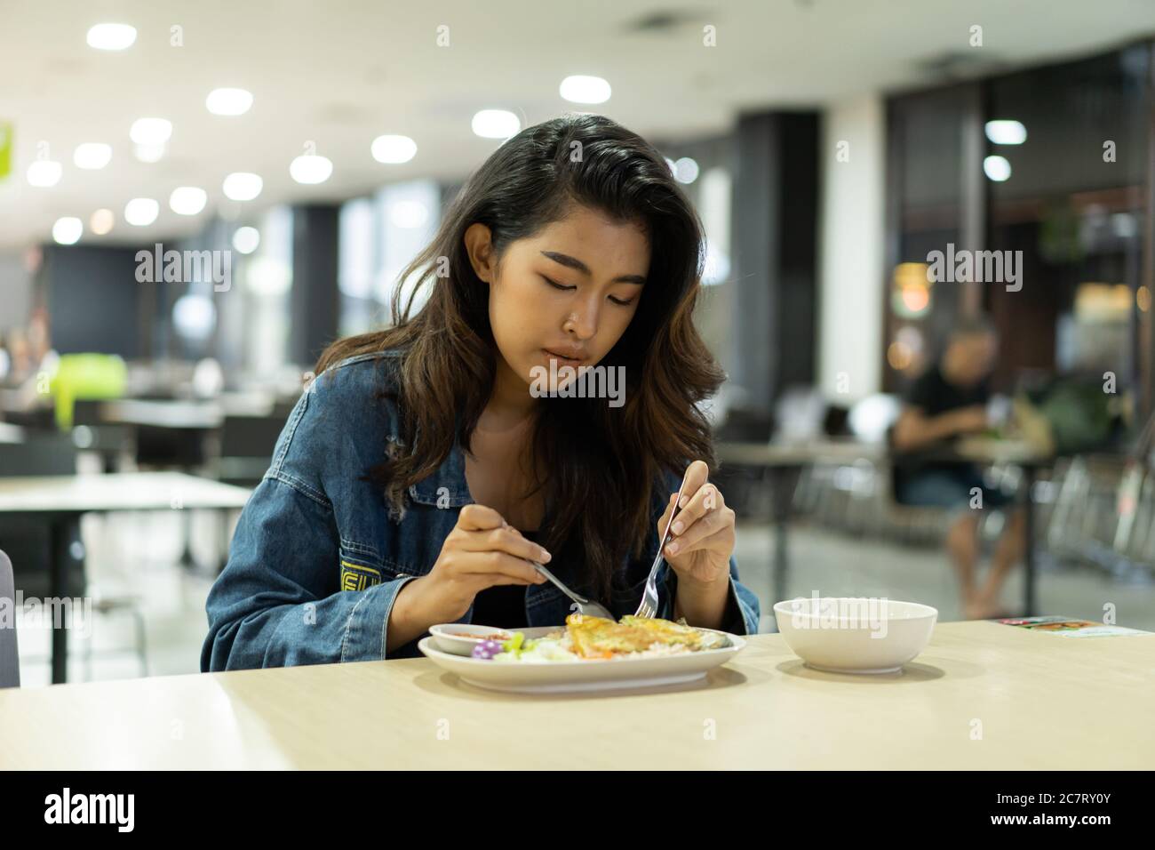 Young Asian woman sitting in cafeteria eating meal. Beautiful Asia girl ...