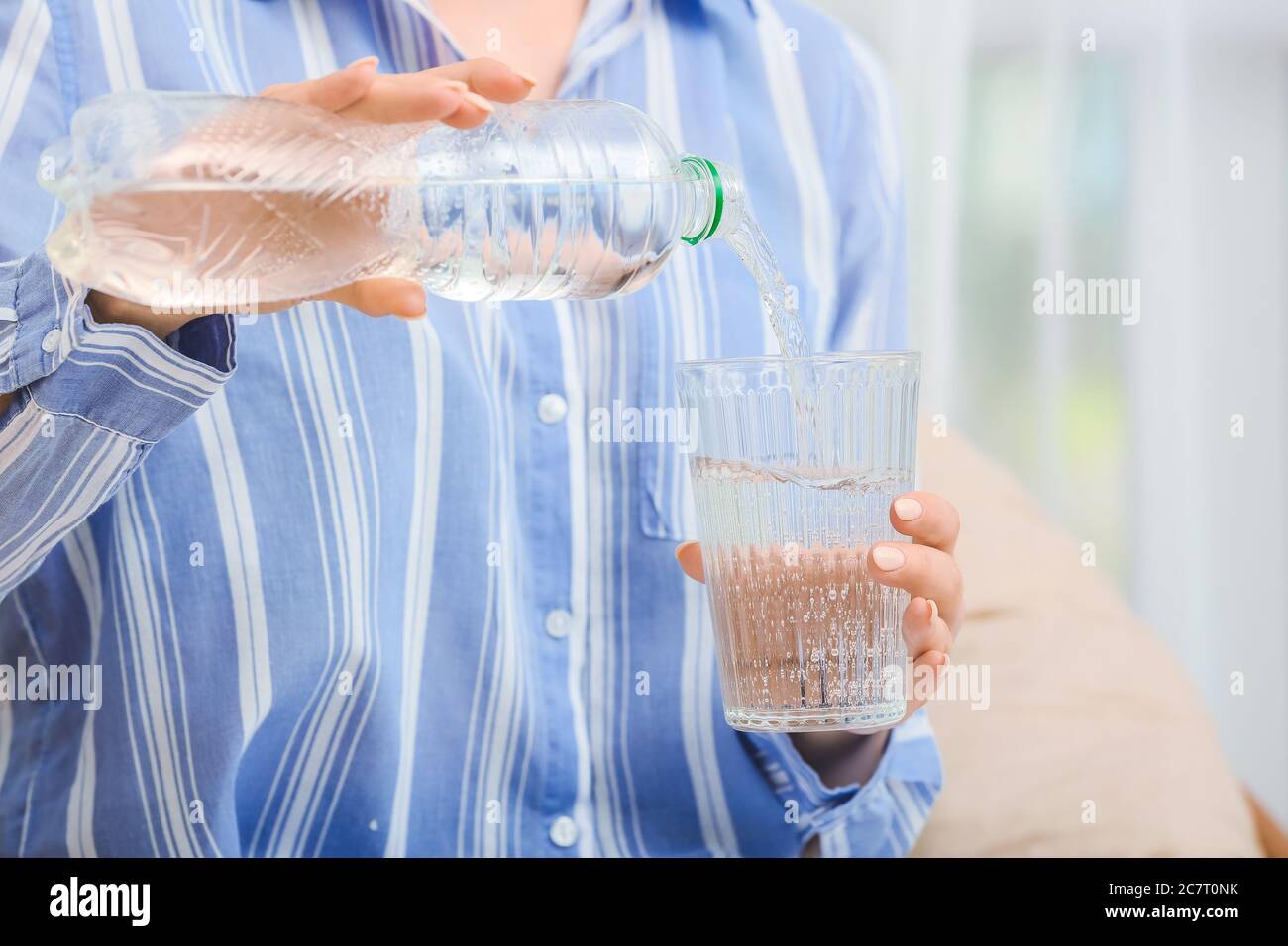 Woman pouring water into glass at home Stock Photo - Alamy