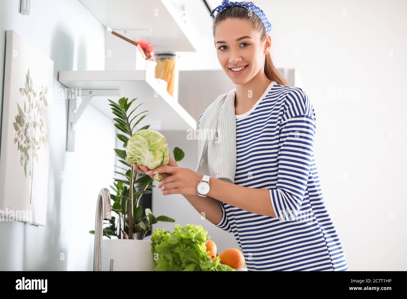 Beautiful young woman washing fresh vegetables in kitchen Stock Photo ...