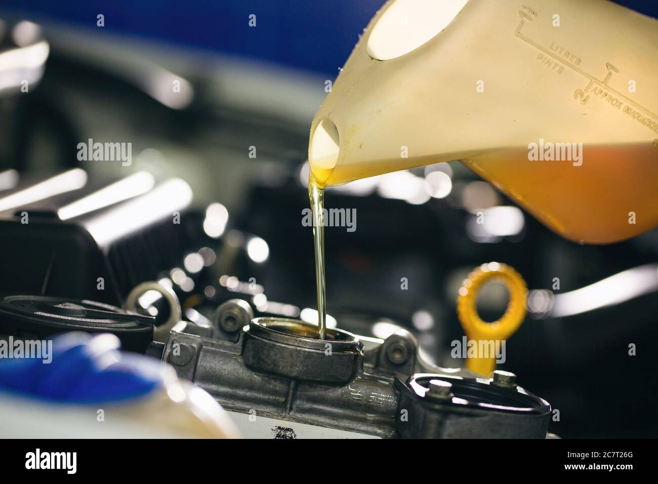 Auto mechanic is changing motor oil into a engine at car station. Close ...