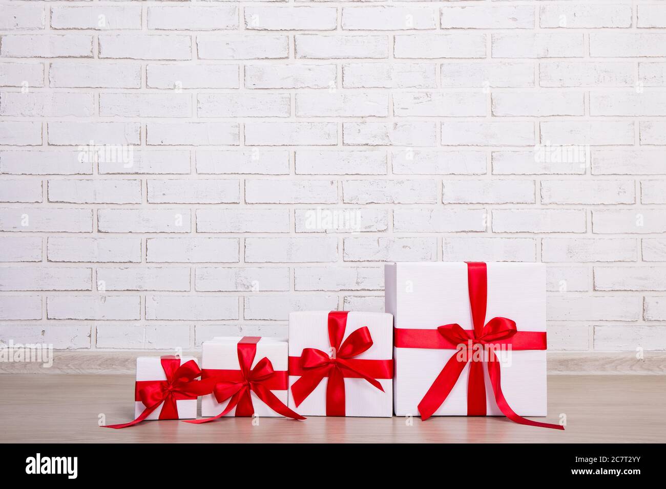 christmas gift boxes over white brick wall Stock Photo - Alamy