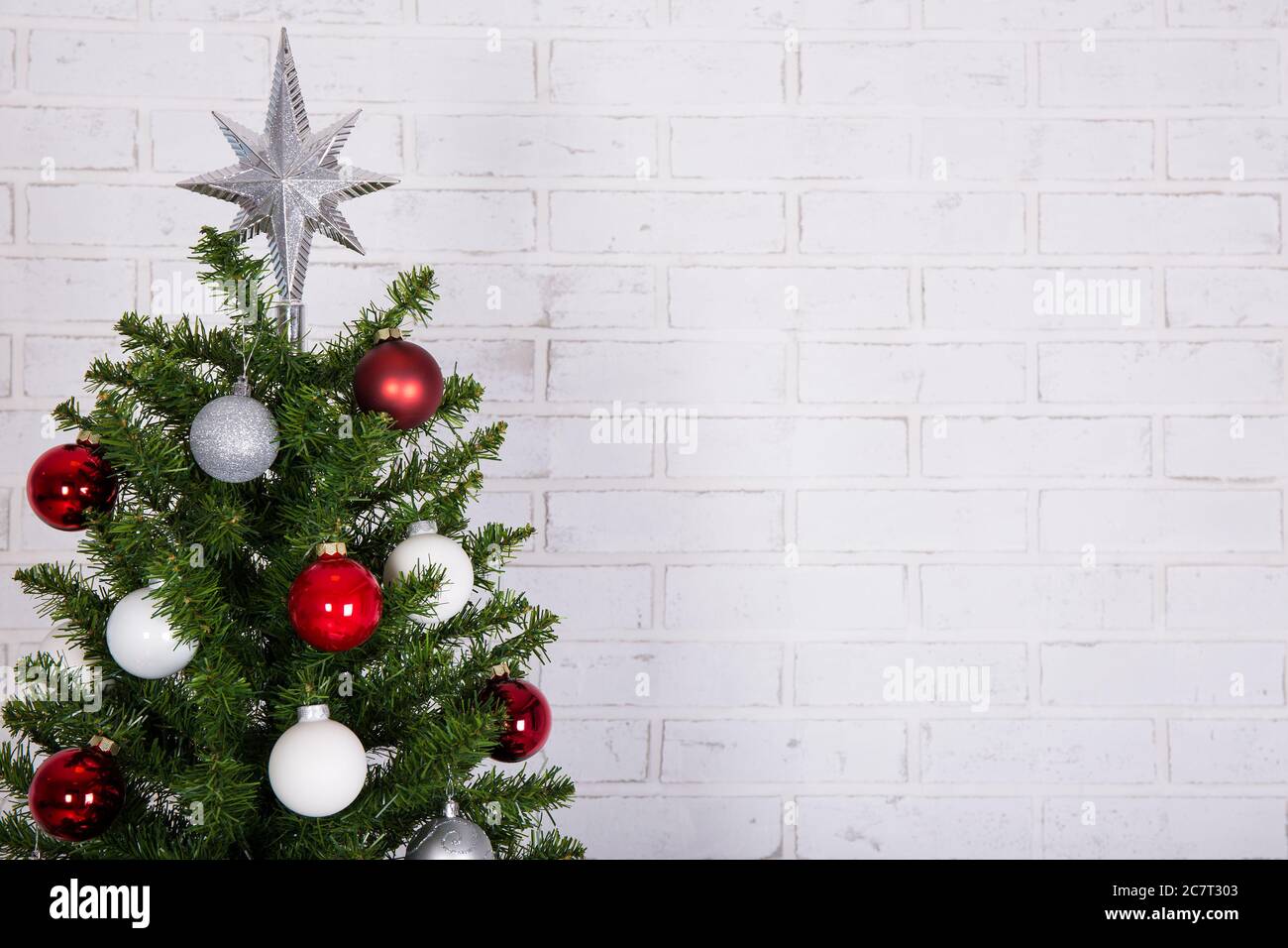 Close up of decorated christmas tree over white brick wall Stock Photo ...