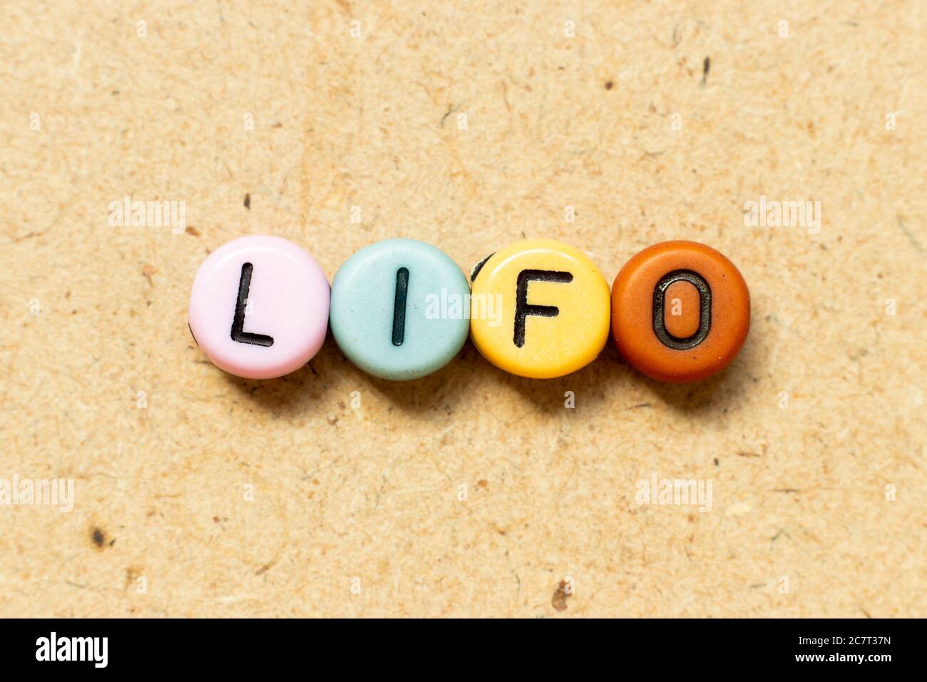 Round color bead with black letter in word LIFO (abbreviation of last in first out) on wood ...