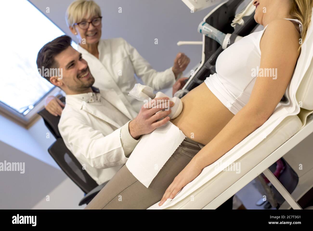 Cheerful male doctor examining a female patient using an ultrasound ...