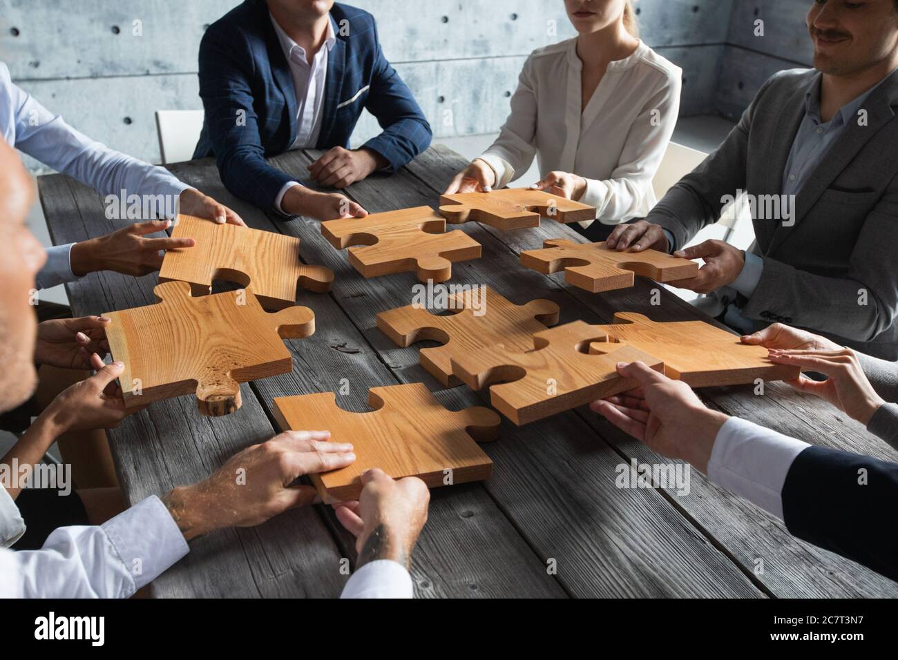 Business people team sitting around meeting table and assembling wooden ...