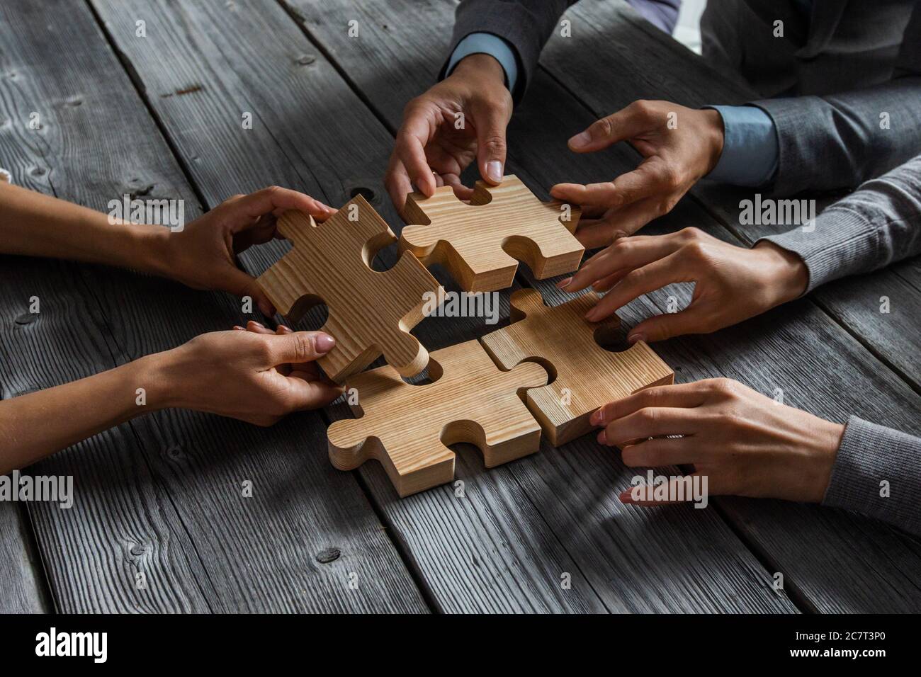Business people team sitting around meeting table and assembling wooden ...