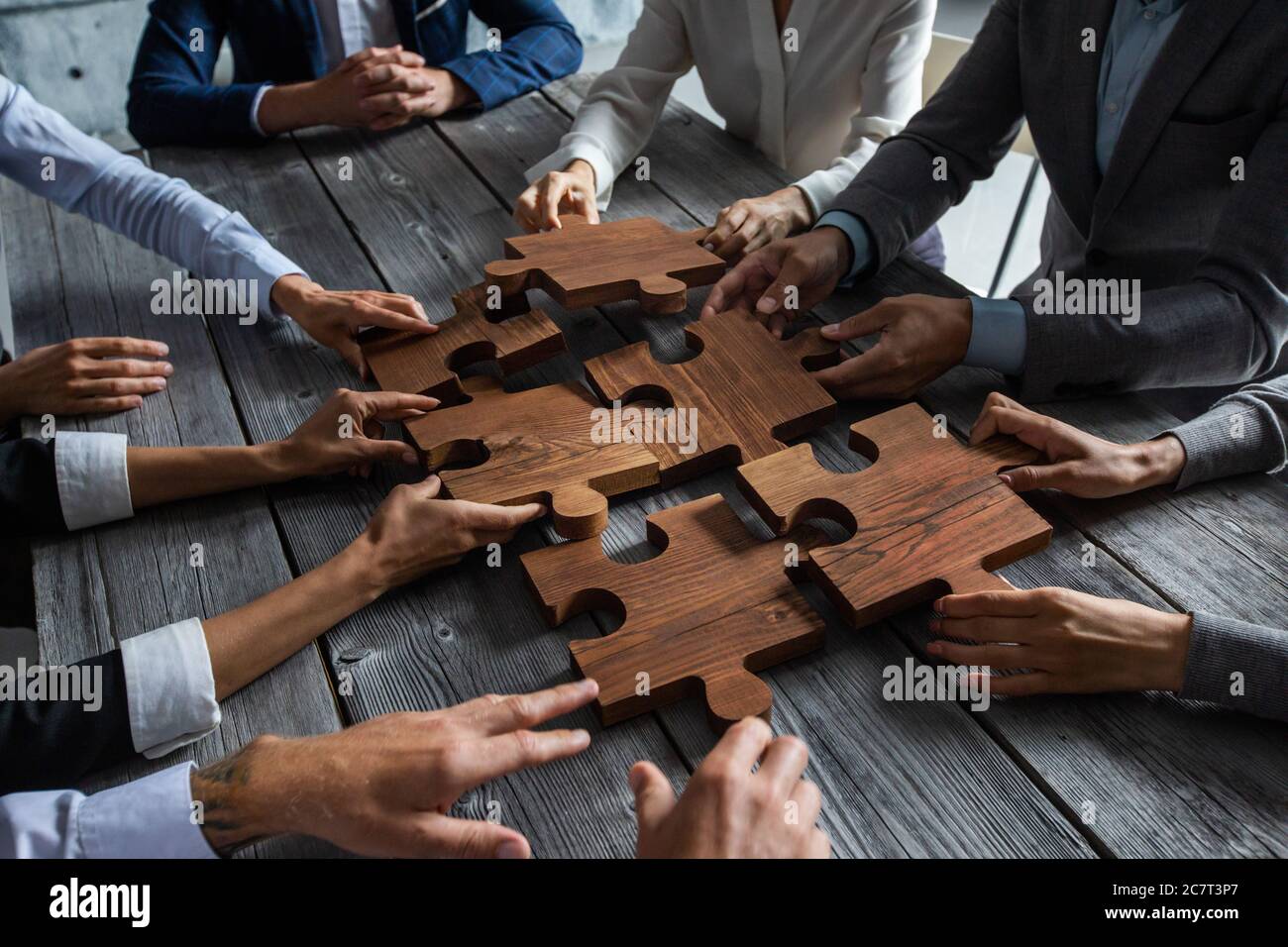 Business people team sitting around meeting table and assembling wooden ...