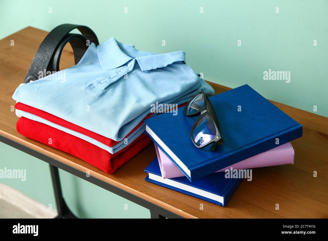 Stylish school uniform with books and eyeglasses on table near color ...