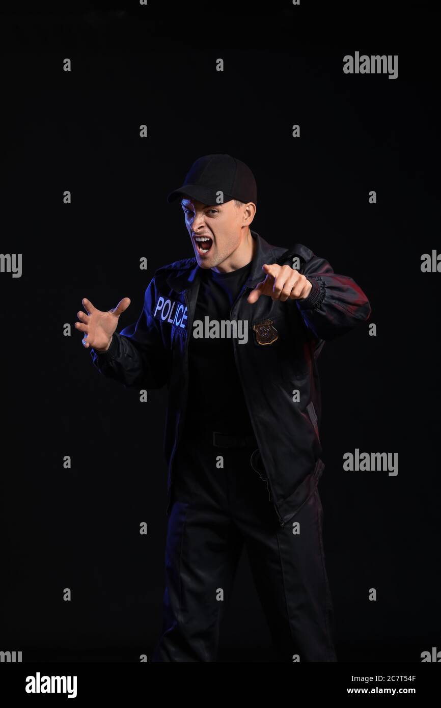 Aggressive police officer on dark background Stock Photo - Alamy