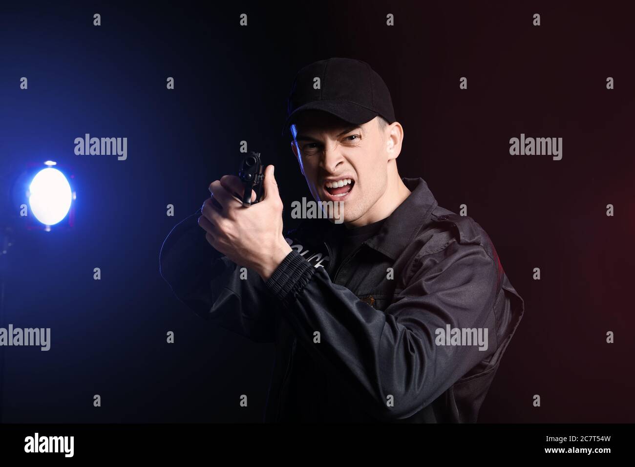 Aggressive police officer with gun on dark background Stock Photo - Alamy