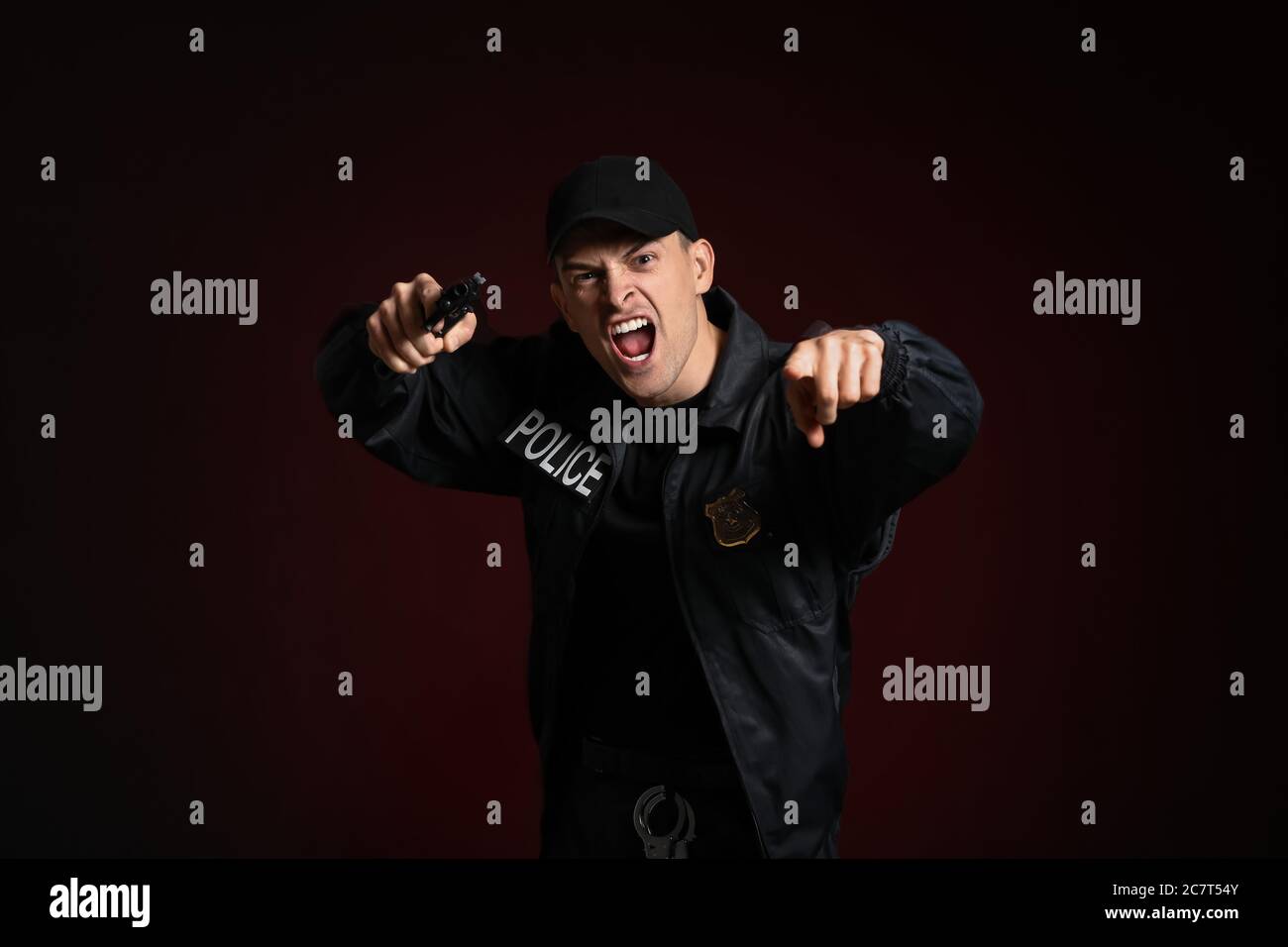 Aggressive police officer with gun on dark background Stock Photo - Alamy