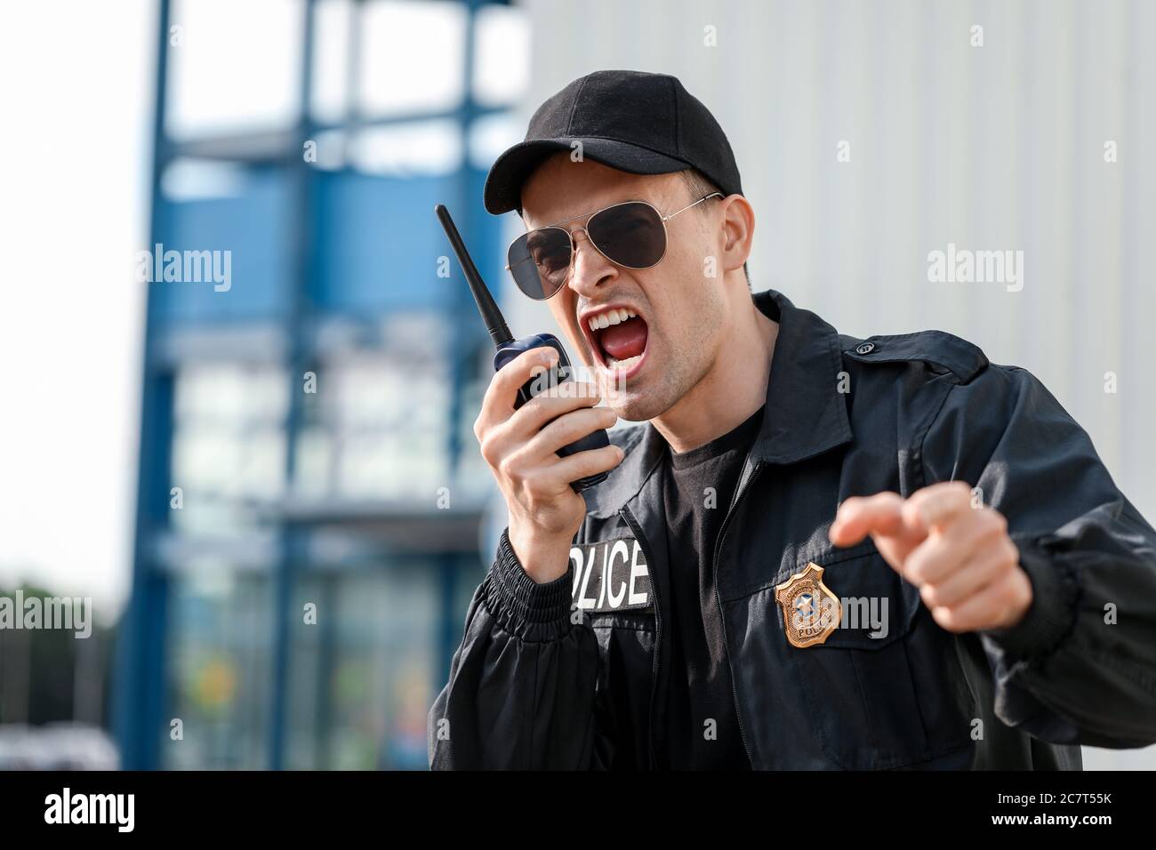 Aggressive police officer with two-way radio outdoors Stock Photo - Alamy