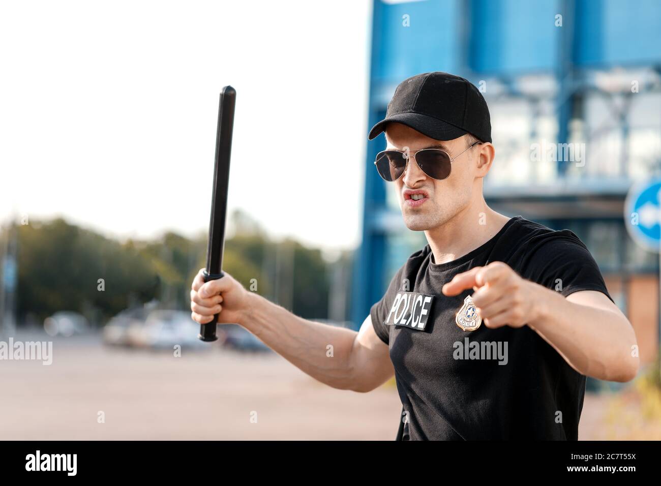 Aggressive police officer with baton outdoors Stock Photo - Alamy