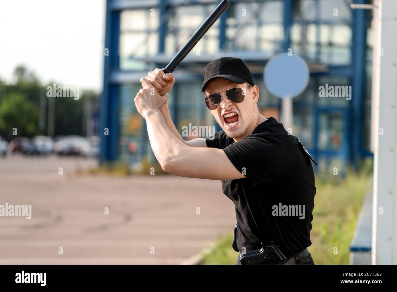 Aggressive police officer with baton outdoors Stock Photo - Alamy