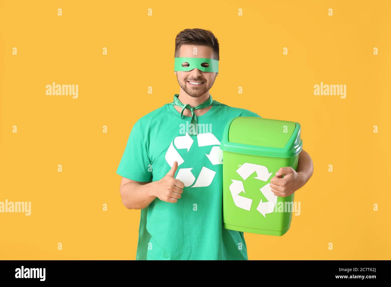 Man dressed as eco superhero with trash bin showing thumb-up gesture on ...
