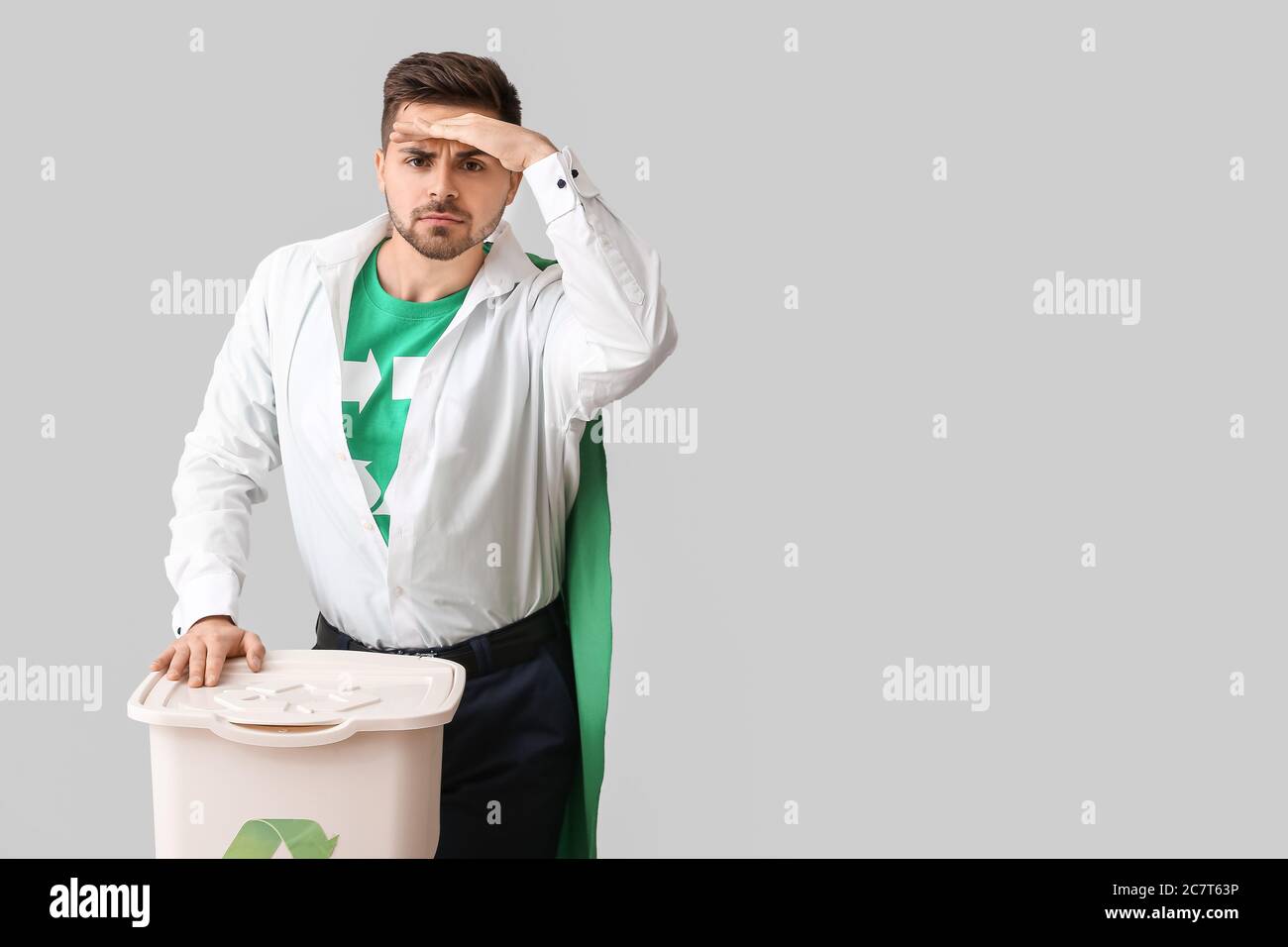 Man dressed as eco superhero with trash bin on grey background Stock ...