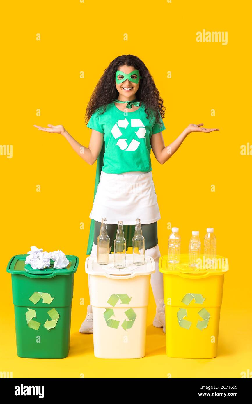 Woman dressed as eco superhero with trash bins on color background ...
