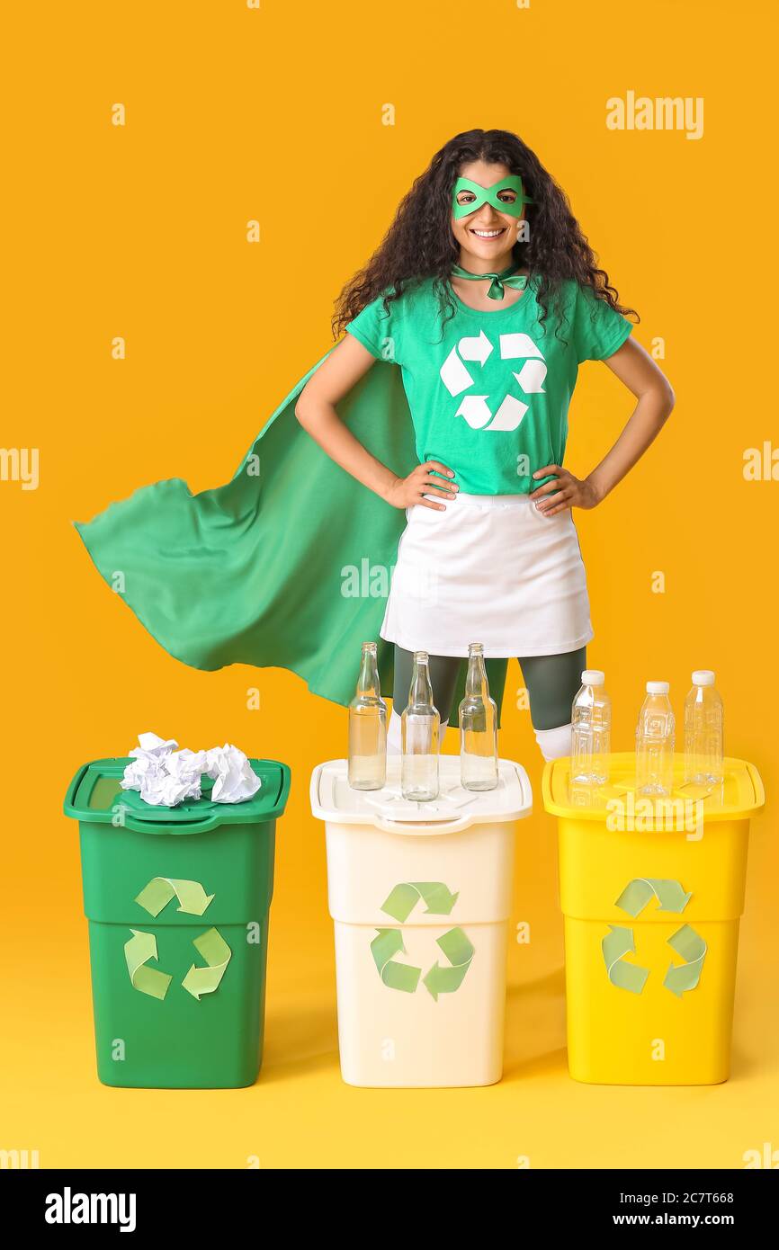 Woman dressed as eco superhero with trash bins on color background ...