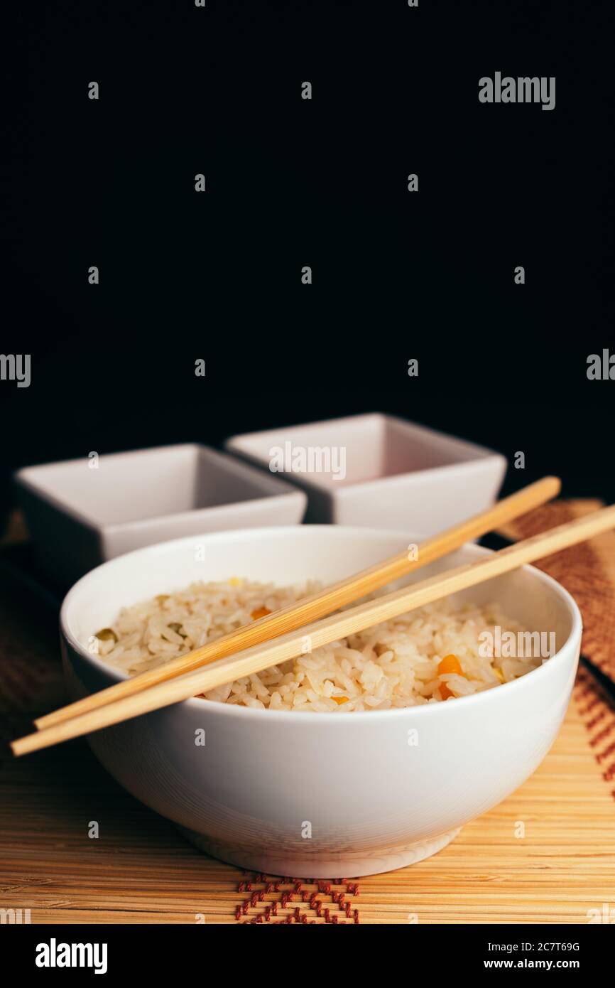 Vertical shot of a bowl of cooked rice with chopsticks on it on the ...