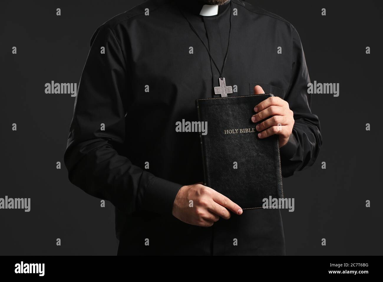 Young priest with Bible on dark background Stock Photo - Alamy
