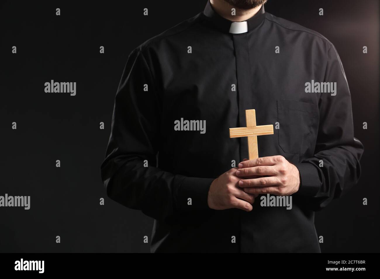 Young priest with cross on dark background Stock Photo - Alamy